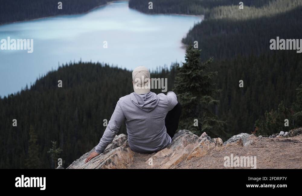 A Guy Sitting On The Rocky Ground Viewing The Scenic Peyto Lake In ...