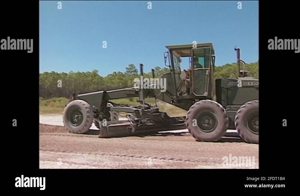 2000s: Military construction grader levels dirt in field. Construction ...