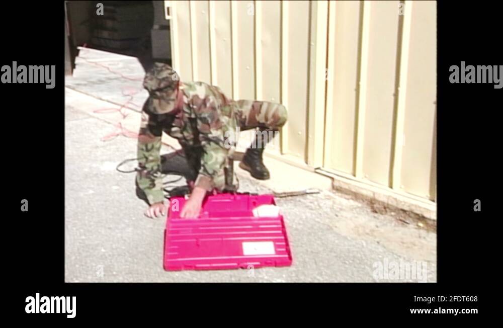 2000s: Man in army fatigues kneeling on ground, holds hammer drill in ...