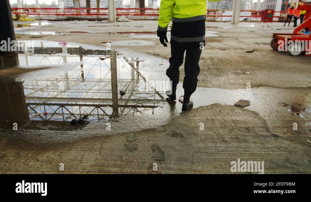 Rear view of man worker walking outdoors on construction site, carrying ...