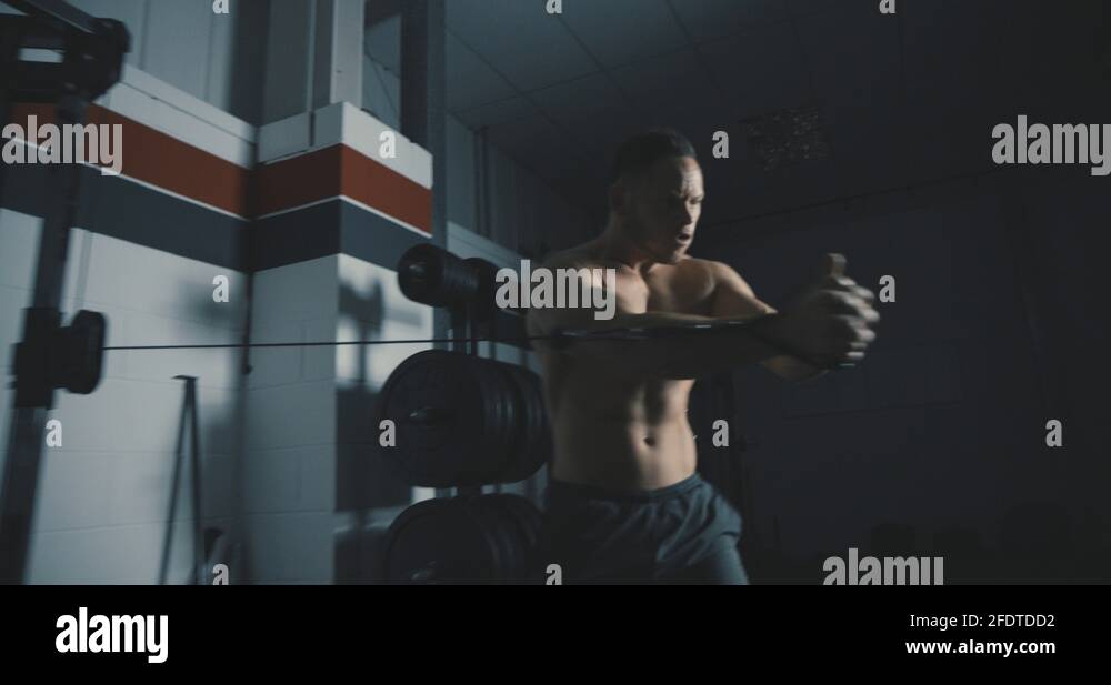 Male fitness athlete cable twist rotations inside a moody lit gym Stock ...