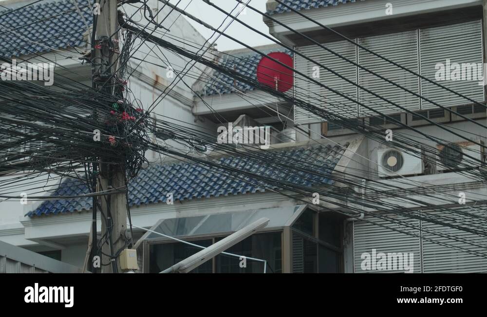 Messy power lines in Thailand with old residential building in the ...