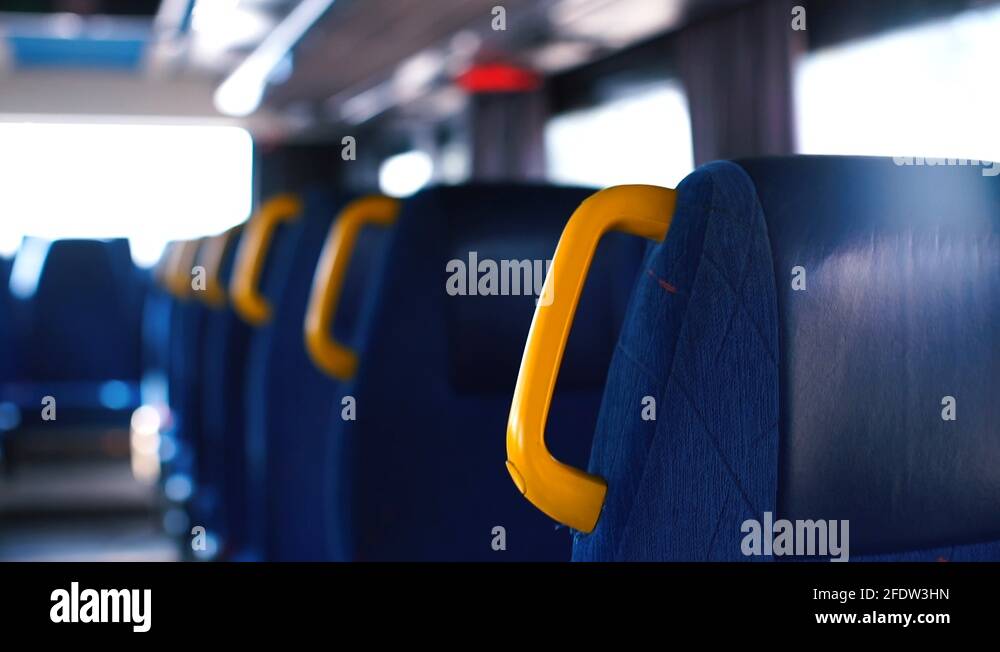 Yellow handrails in an empty moving bus. Blue color of seats. Public ...