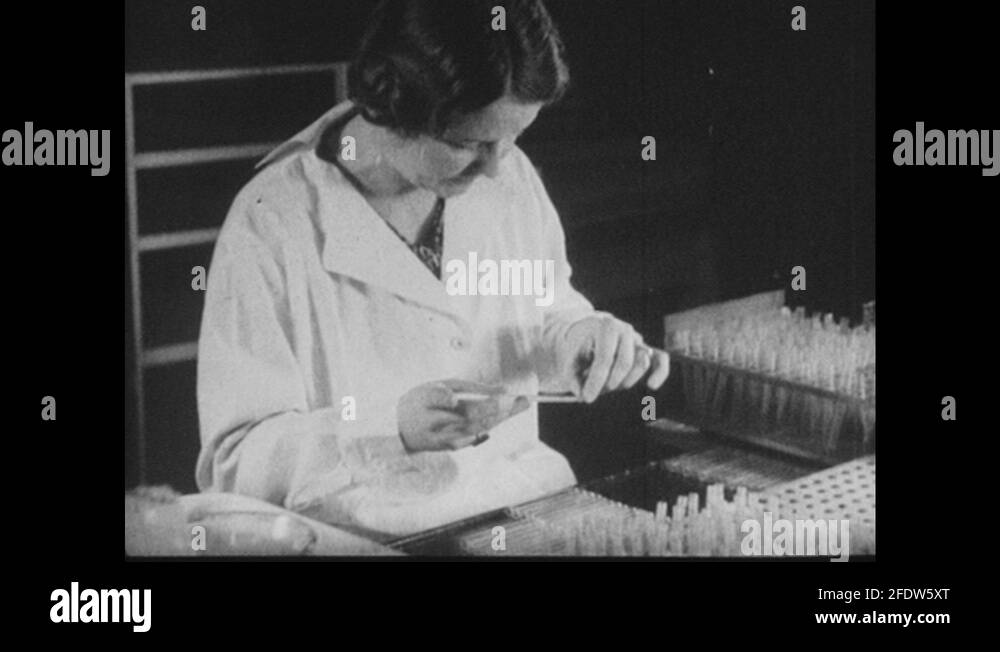 1950s: Woman adds antigen to blood vials with pipette. Man holds sample ...