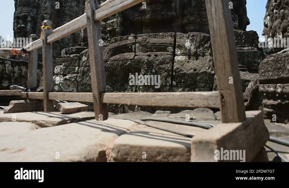 Wooden railing against damaged face sculptures on structures at ancient ...