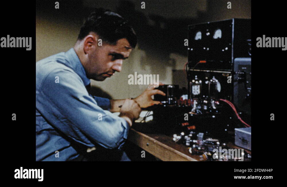 1950s: Man working with electronic equipment. Men look at model of ...