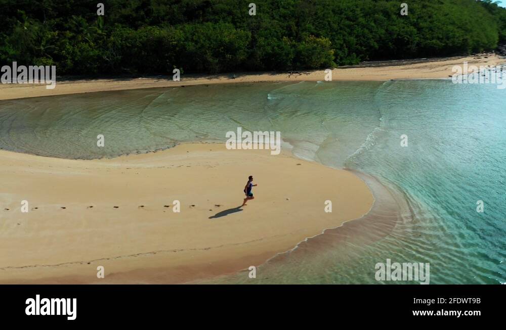 Man running to the end of a beach spreading his arms out of enjoyment ...
