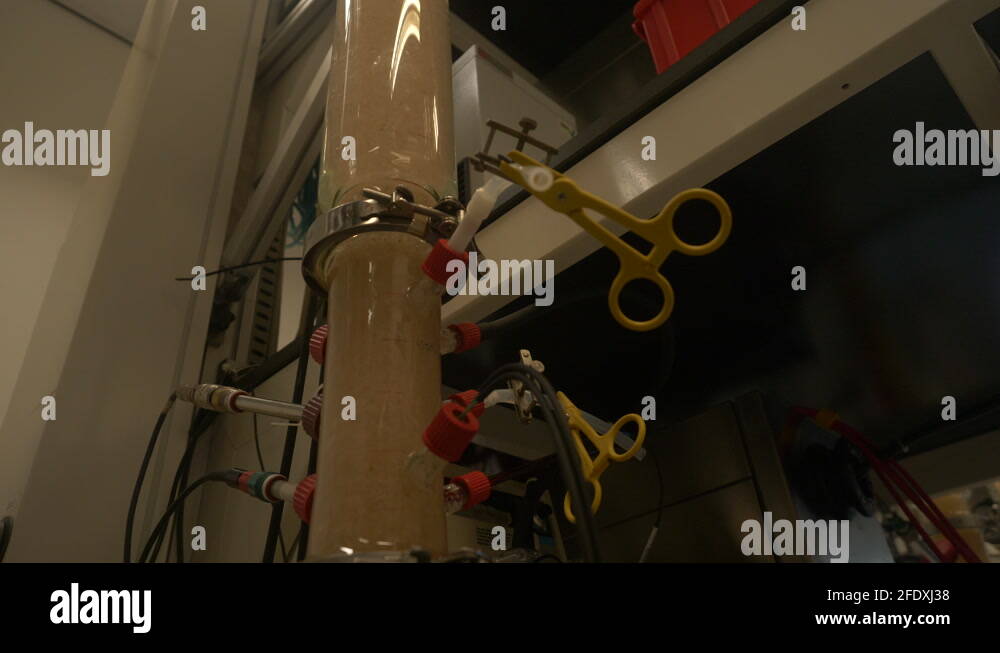 Scissor clamps on a glass test tube beaker with brown liquid bubbling ...