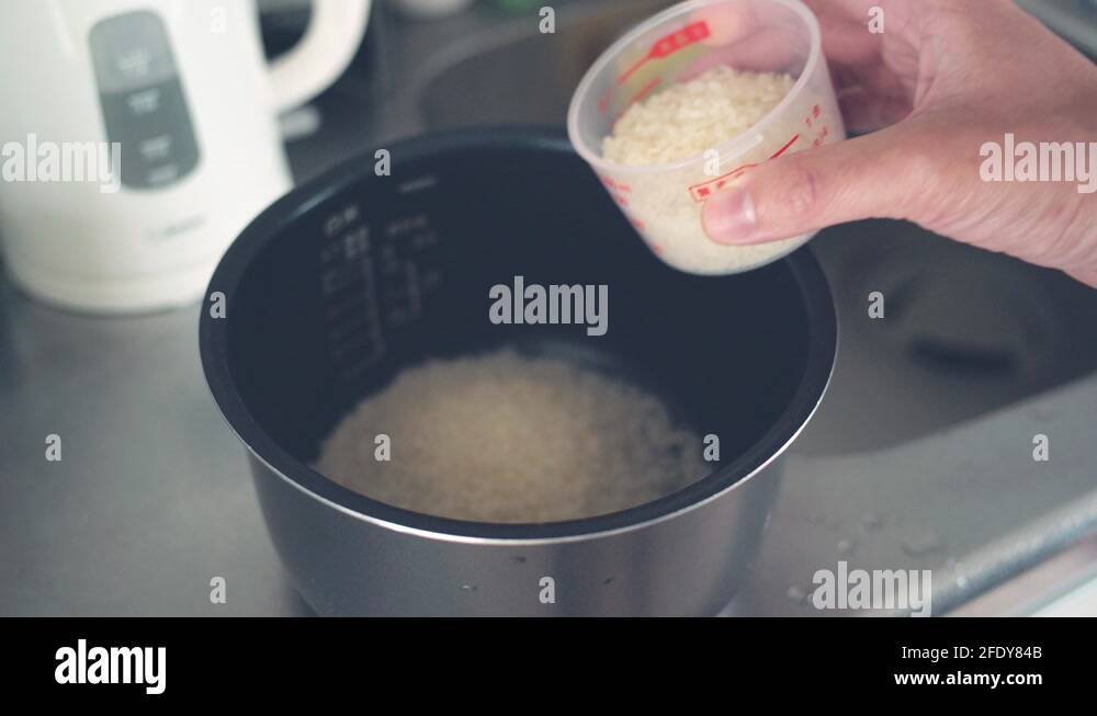 Pouring A White Rice Into A Rice Cooker Bowl Near The Kitchen Sink Of A ...