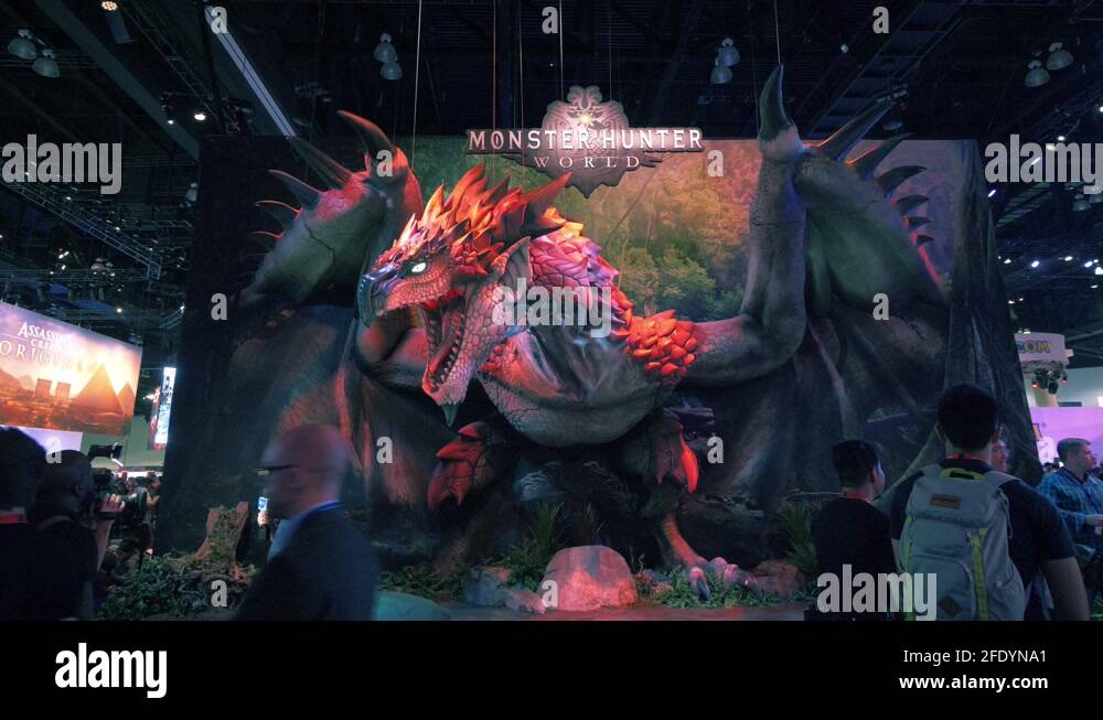 People walking by Monster Hunter: World booth at E3 expo. Giant dragon ...