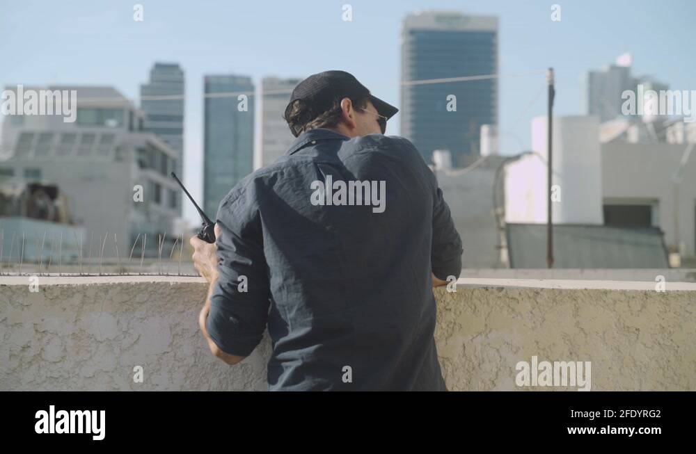 Special agent security guard watching from city rooftop with walkie ...