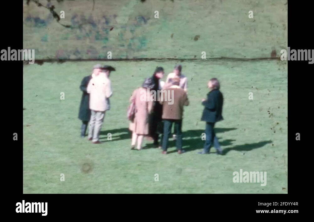 1960s: Crowd of people sit in stadium benches. People walk cross field ...