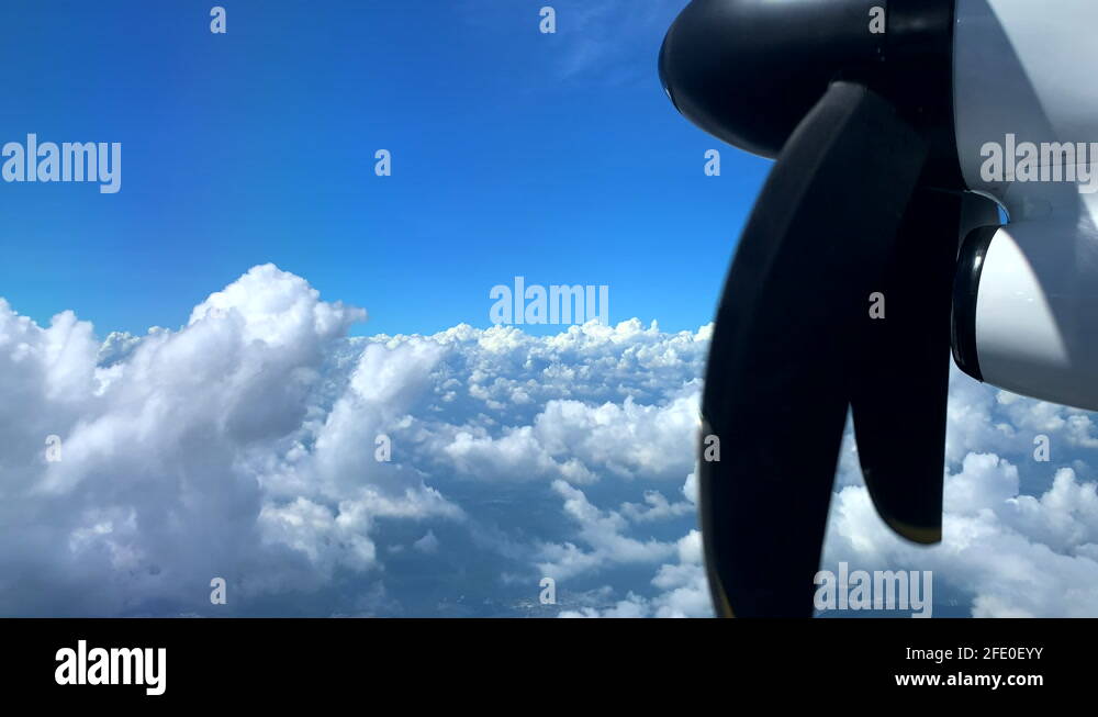 Propeller engine of an airplane flying across the blue sky with white ...