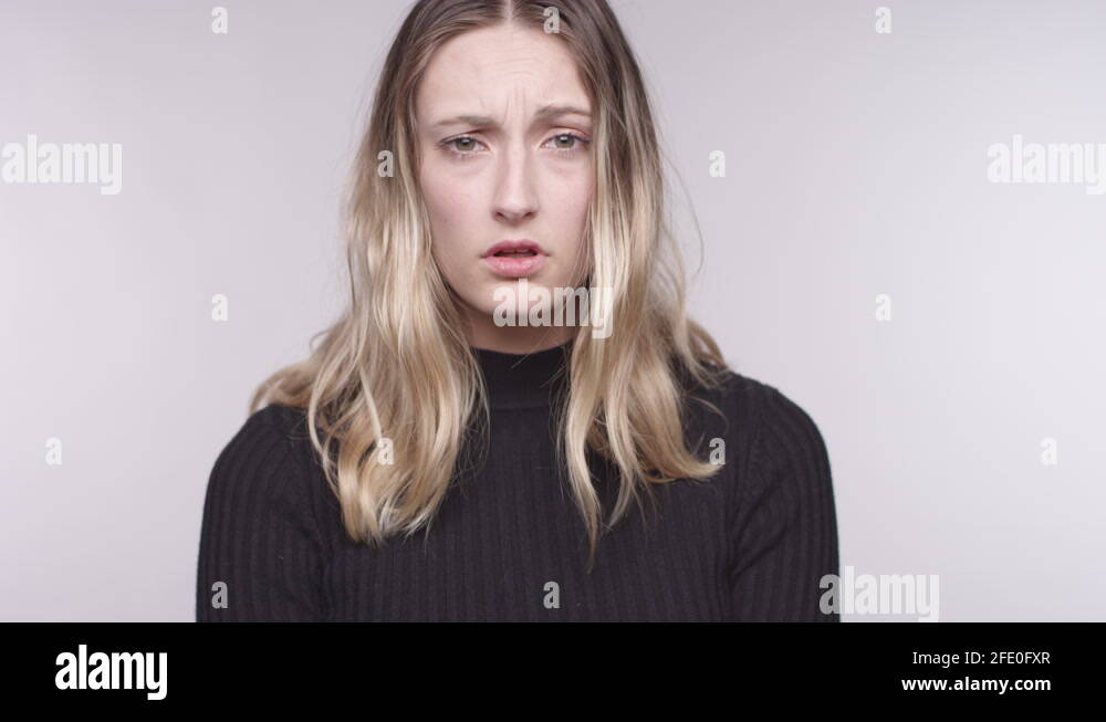 Beautiful young blonde woman is shocked and scared while grabbing her ...