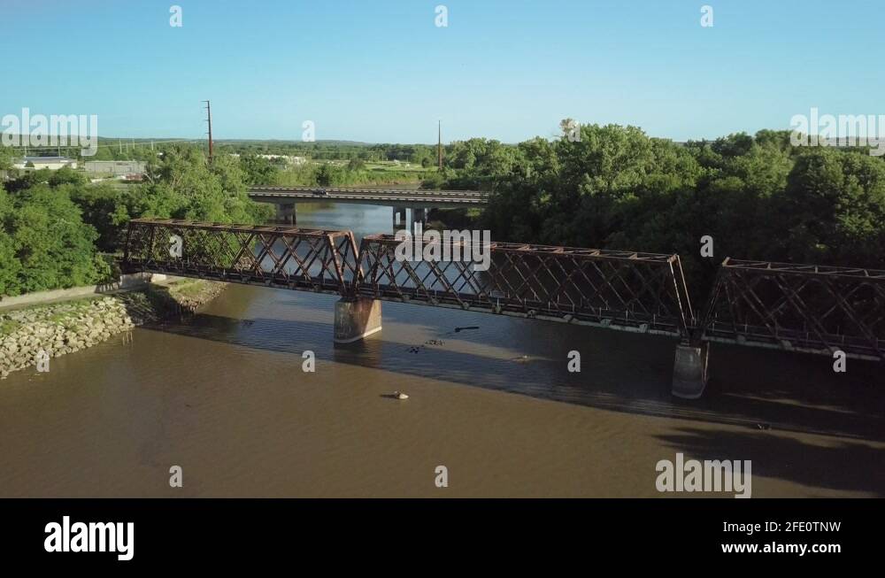 Steel truss railroad bridge above brown river and vehicular bridge in ...