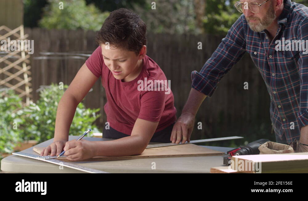 Father helps his son on a DIY backyard construction project on a summer ...