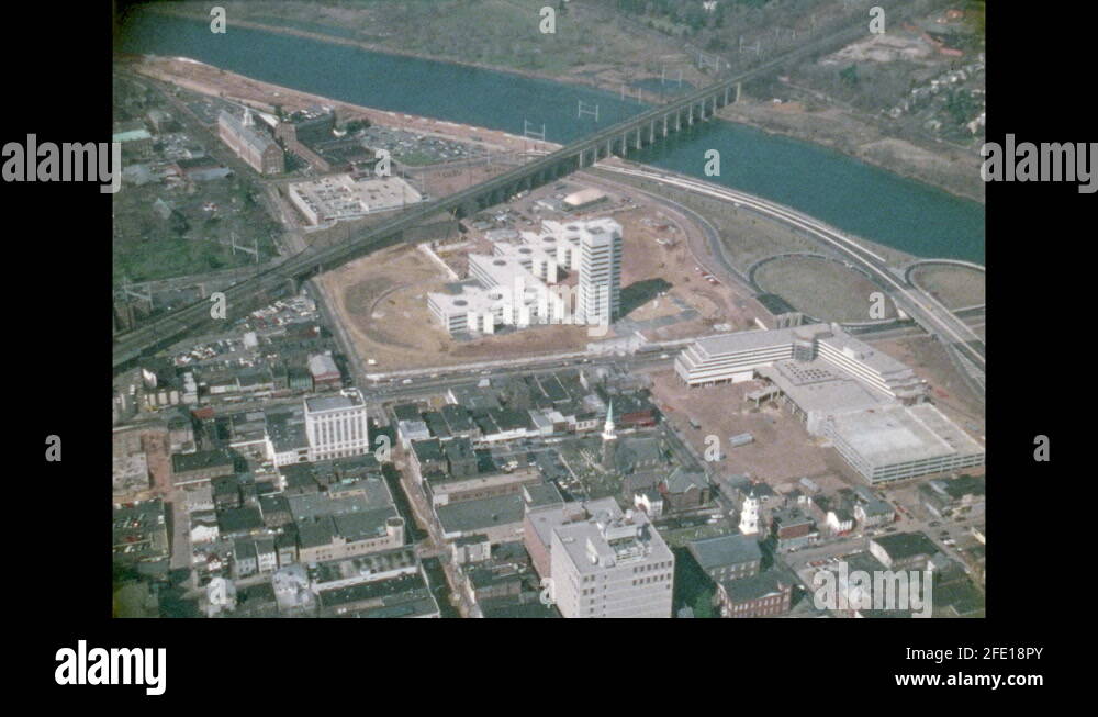 1970s: aerial view of city with buildings, cars moving along streets ...