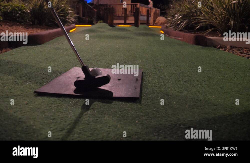 Cinematic shot of a ball getting into the hole in a mini golf at night ...