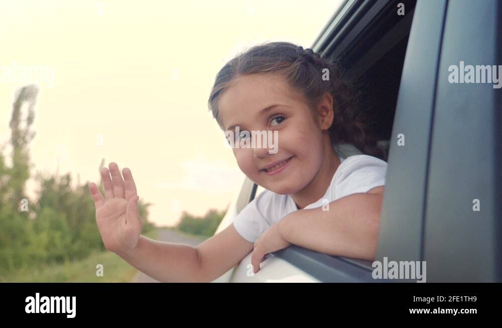 happy girl kid child smile leaned out of a car window waving hand ...