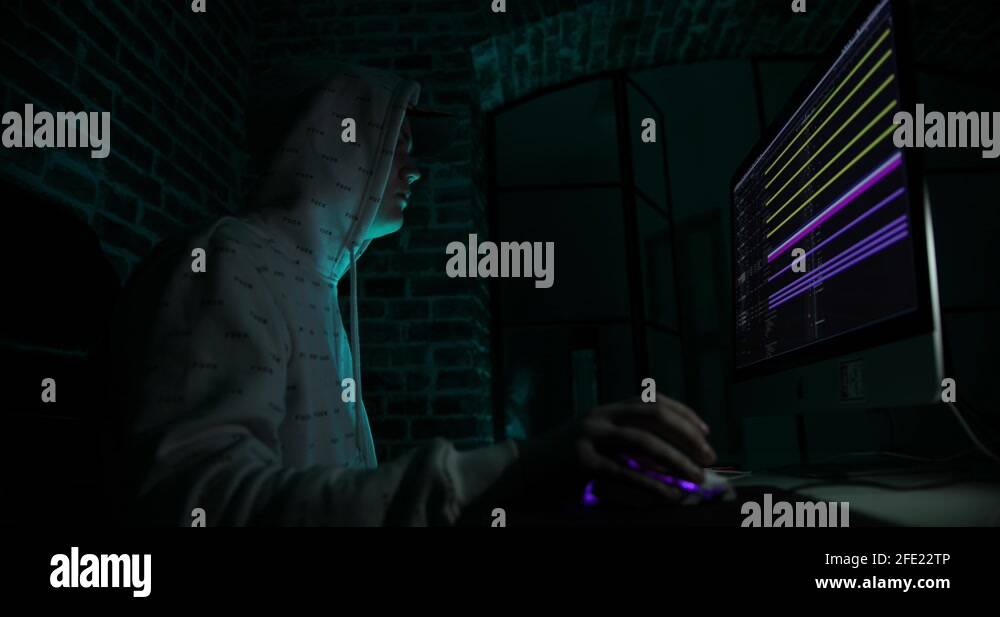 Hacker in the hood working with computer typing text in dark room ...