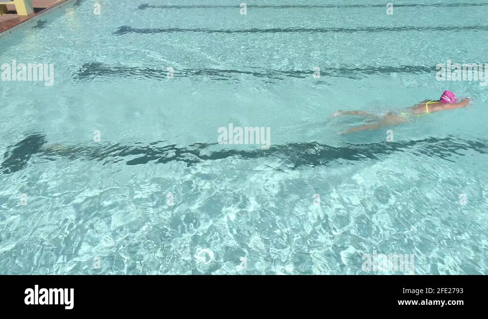 footage of a female swimmer swimming laps in an outdoor pool using the ...