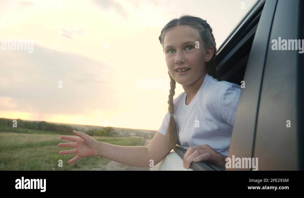 happy girl kid child leaned out of a car window waving hand. happy ...