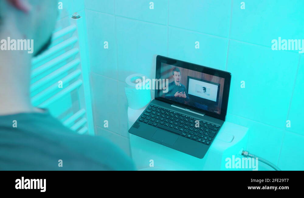 Man watching webinar on laptop computer while taking a leak in toilet ...
