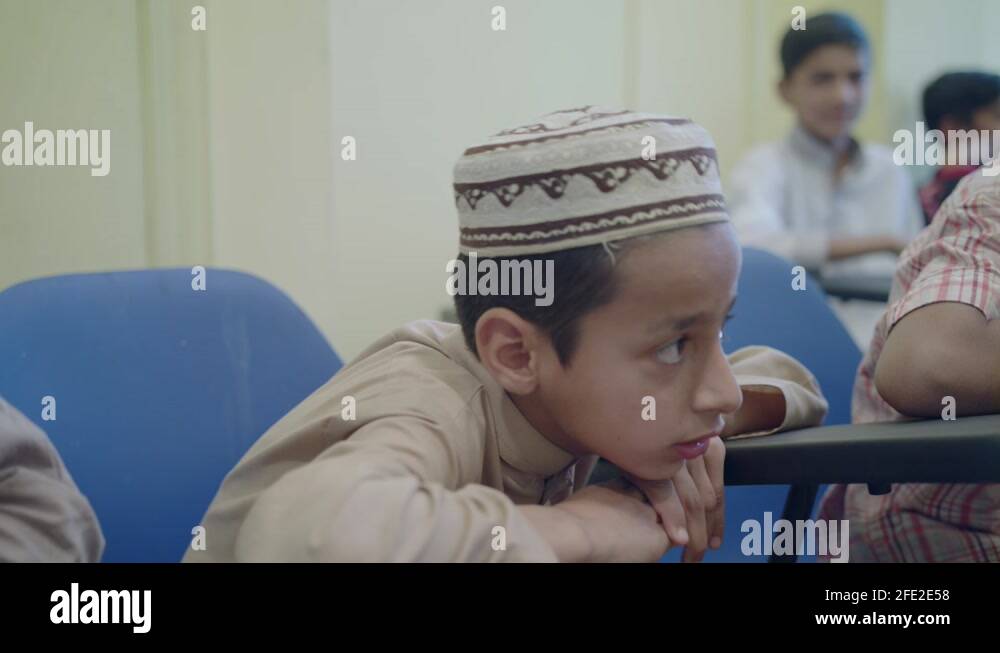 Poor child wearing traditional dress and Muslim cap sitting in the ...
