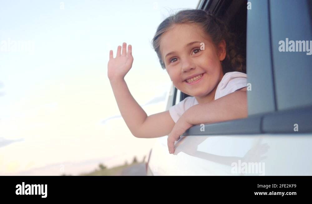 happy girl kid child smile leaned out of a car window waving hand ...