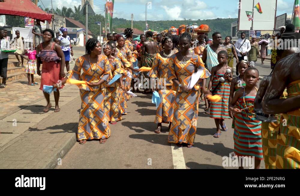 Women dressed in traditional Kente costumes dance and wave ...