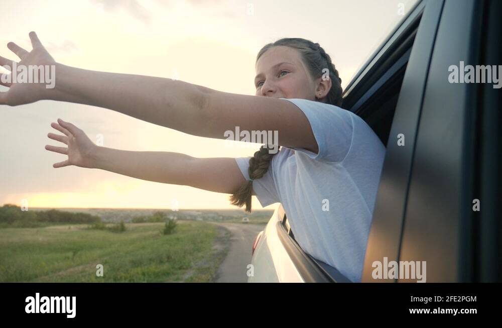 happy girl kid child leaned out of a car window waving hand. happy ...