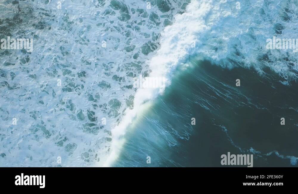 Birds eye view in 4k of a massive blue breaking wave in the stormy ...