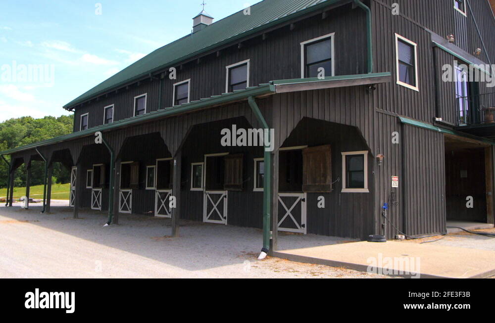 Large wooden two story horse barn with overhang shaded area and open ...