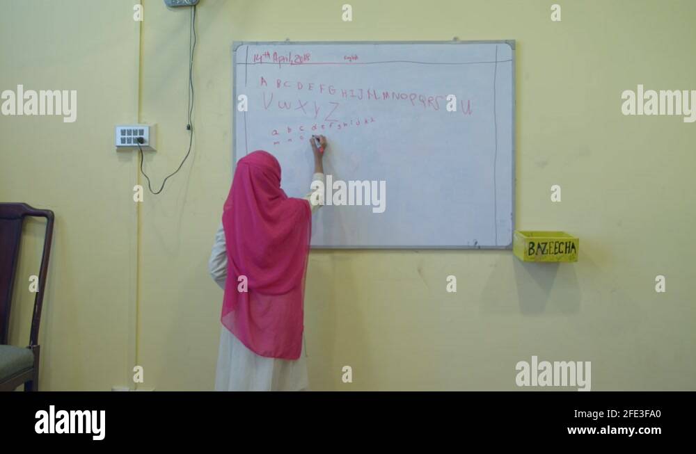 Muslim poor child write 'ABCD' on a whiteboard in a small classroom of ...