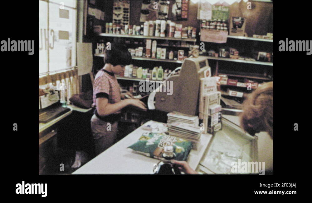 1970s: young boy working at local grocer manning cash register ...