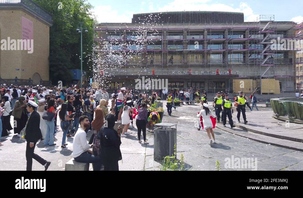 Crowd of students celebrating graduation by setting off confetti ...