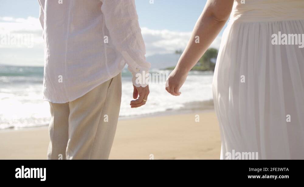 Just Married Caucasian Couple Holding Hands On White Sandy Beach In