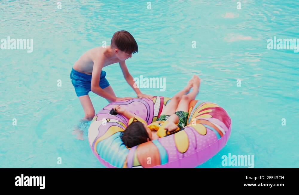 Two boys are playing in the inflatable pool. Cooling the body in sunny ...