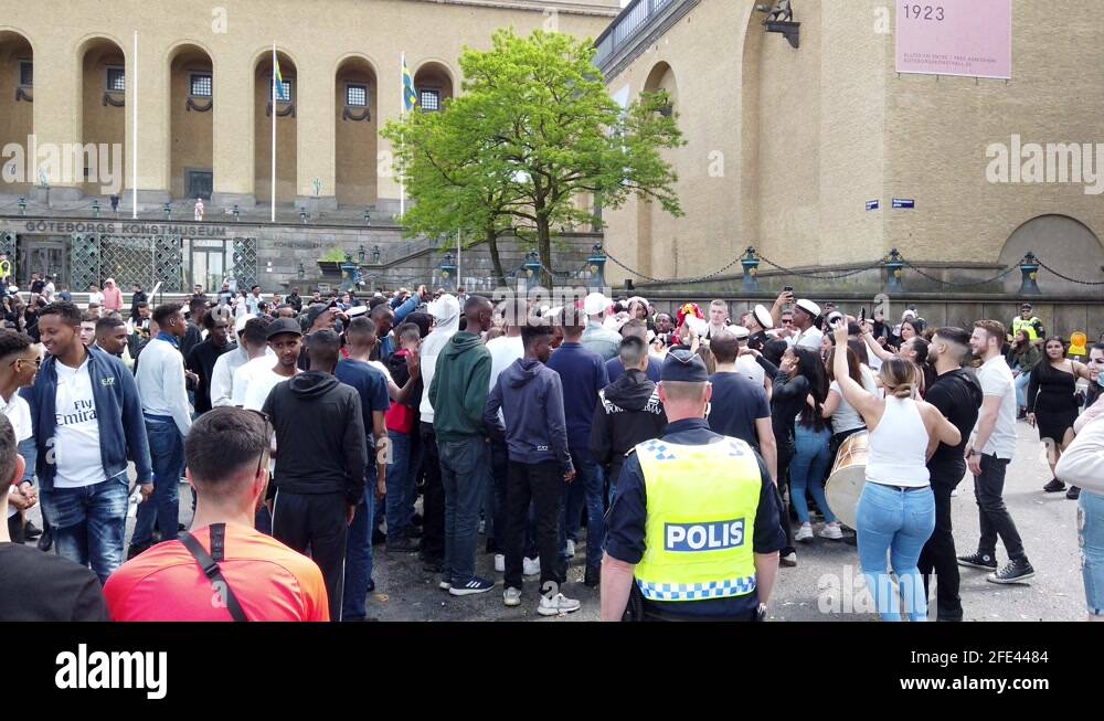 Crowd of young people dancing and cheering with police officer watching ...