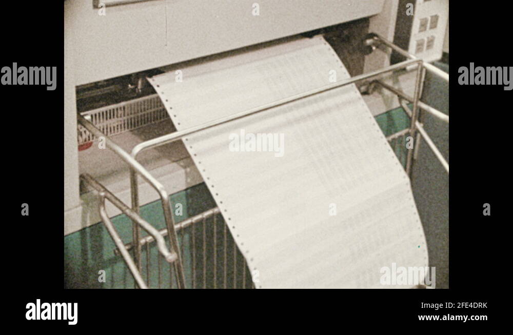 Continuous loop of paper emerges from printer. People sit at desks ...