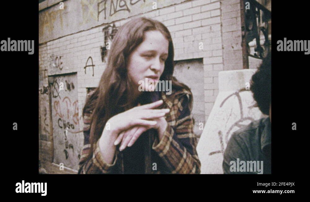 1970s: Woman talking, pan to man sitting on stoop. People on sidewalk ...