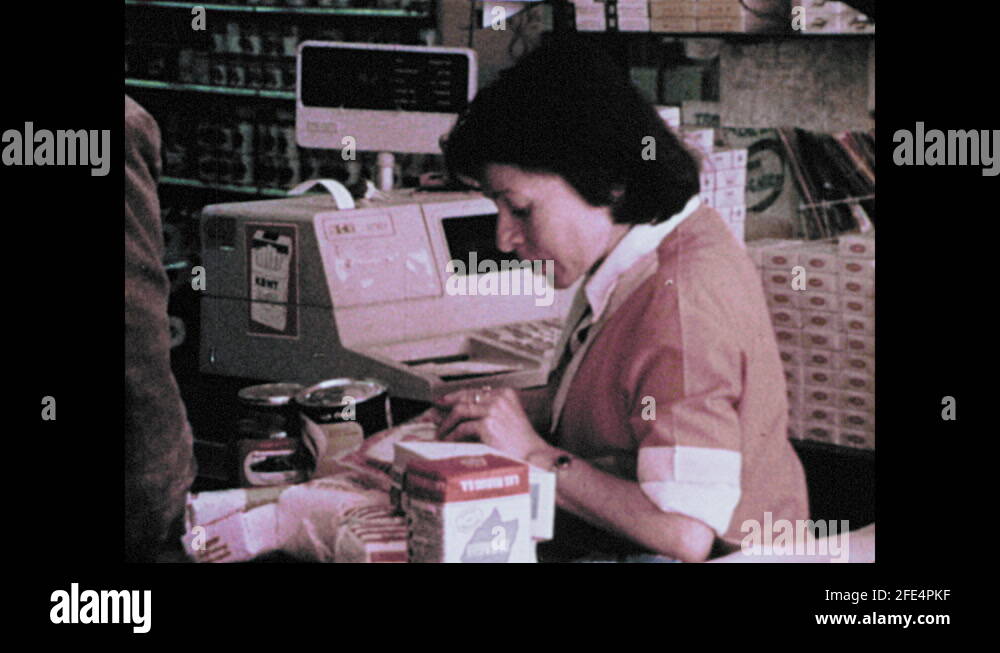 1970s: Checker at register in grocery store. Woman and children on road ...