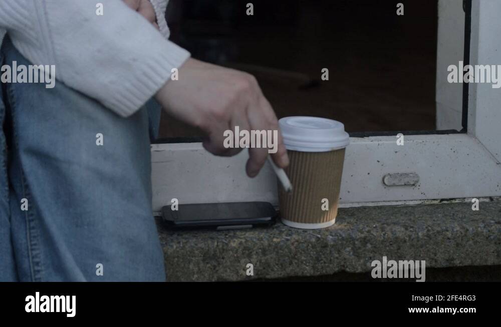 Woman sitting on step smoking cigarette and drinking coffee medium shot ...