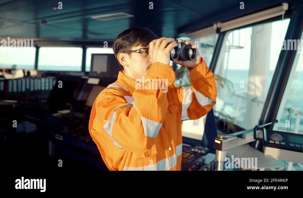 Filipino deck Officer on bridge of vessel or ship looking through ...