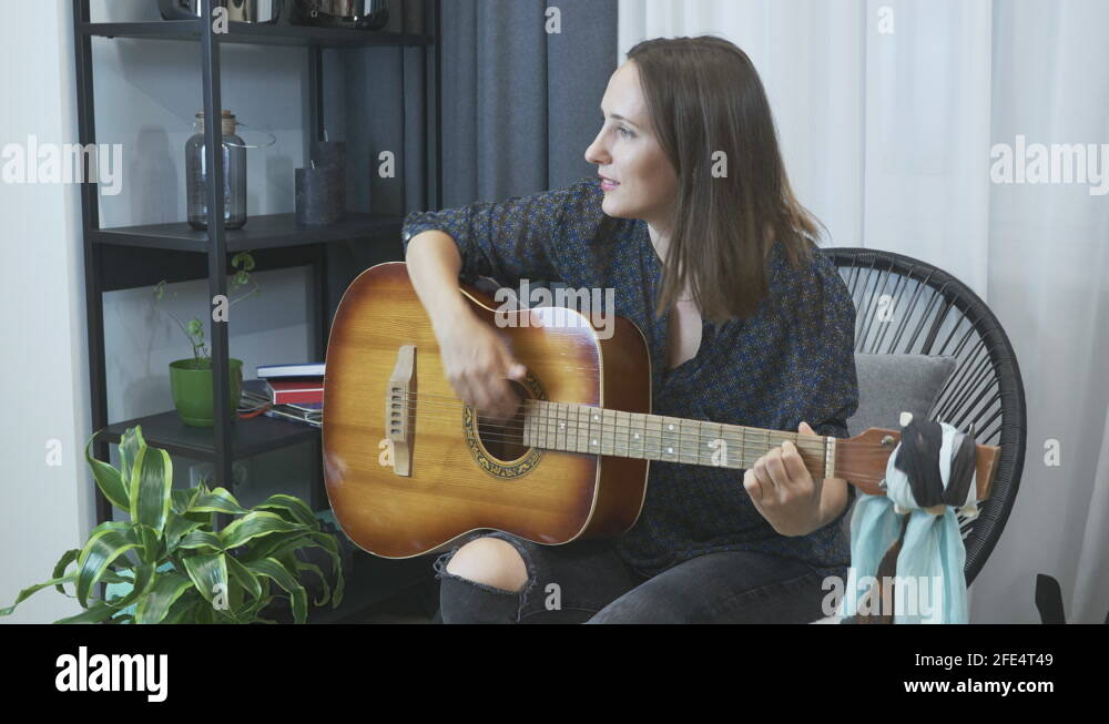 Female guitarist playing acoustic guitar at home. Woman play chords on ...