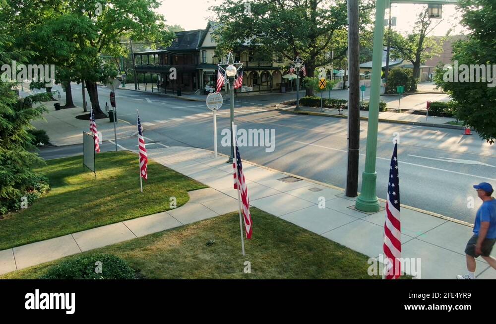 Pedestrian walks on sidewalk through Small Town America scene decorated ...