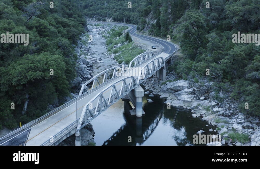 Small bridge crosses over flowing water to connect two sides of valley ...