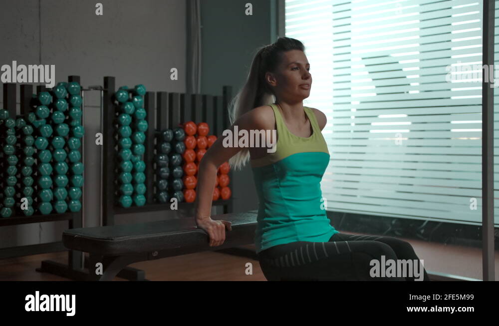Attractive woman in gym doing triceps exercises, bending her arms on ...