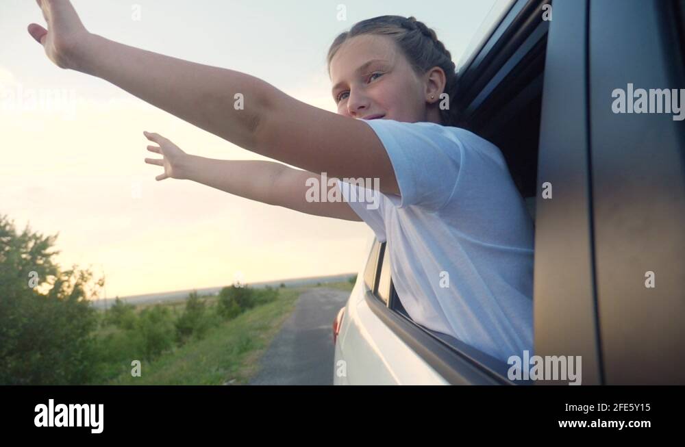 happy girl kid child leaned out of a car window waving hand. happy ...