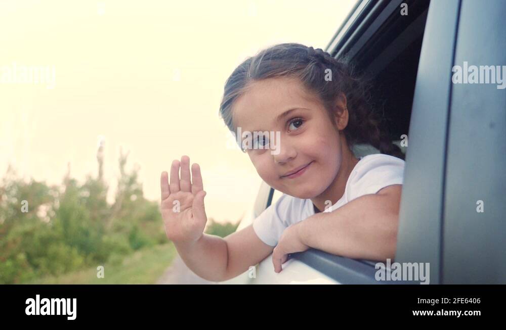 happy girl kid child smile leaned out of a car window waving hand ...